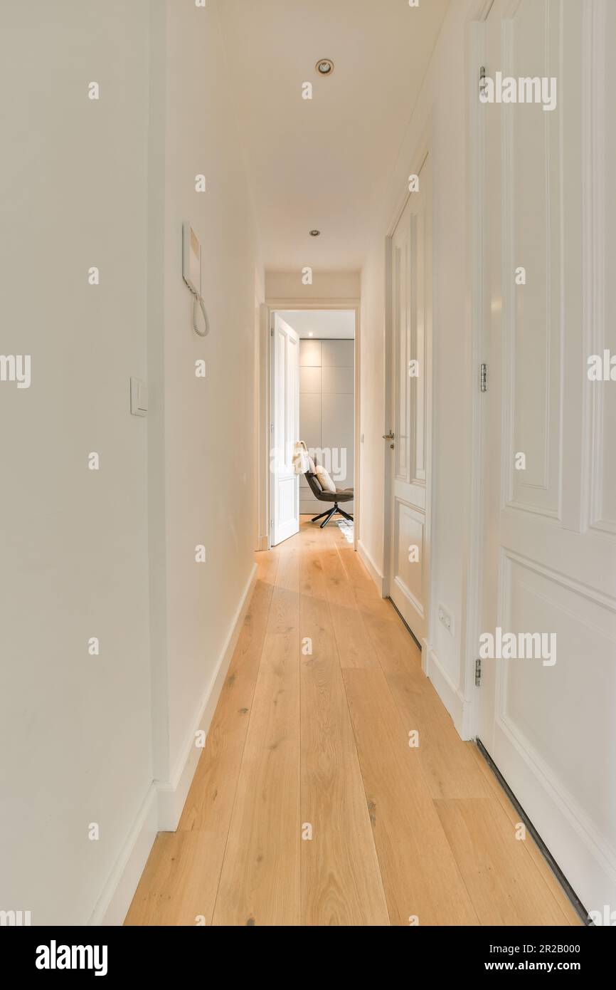 a long hallway with white walls and wood flooring on either side by ...