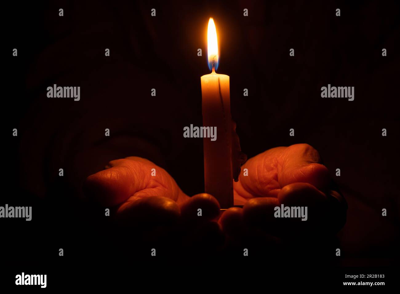 old woman's hands and candle flame in the dark, candle light, mourning ...