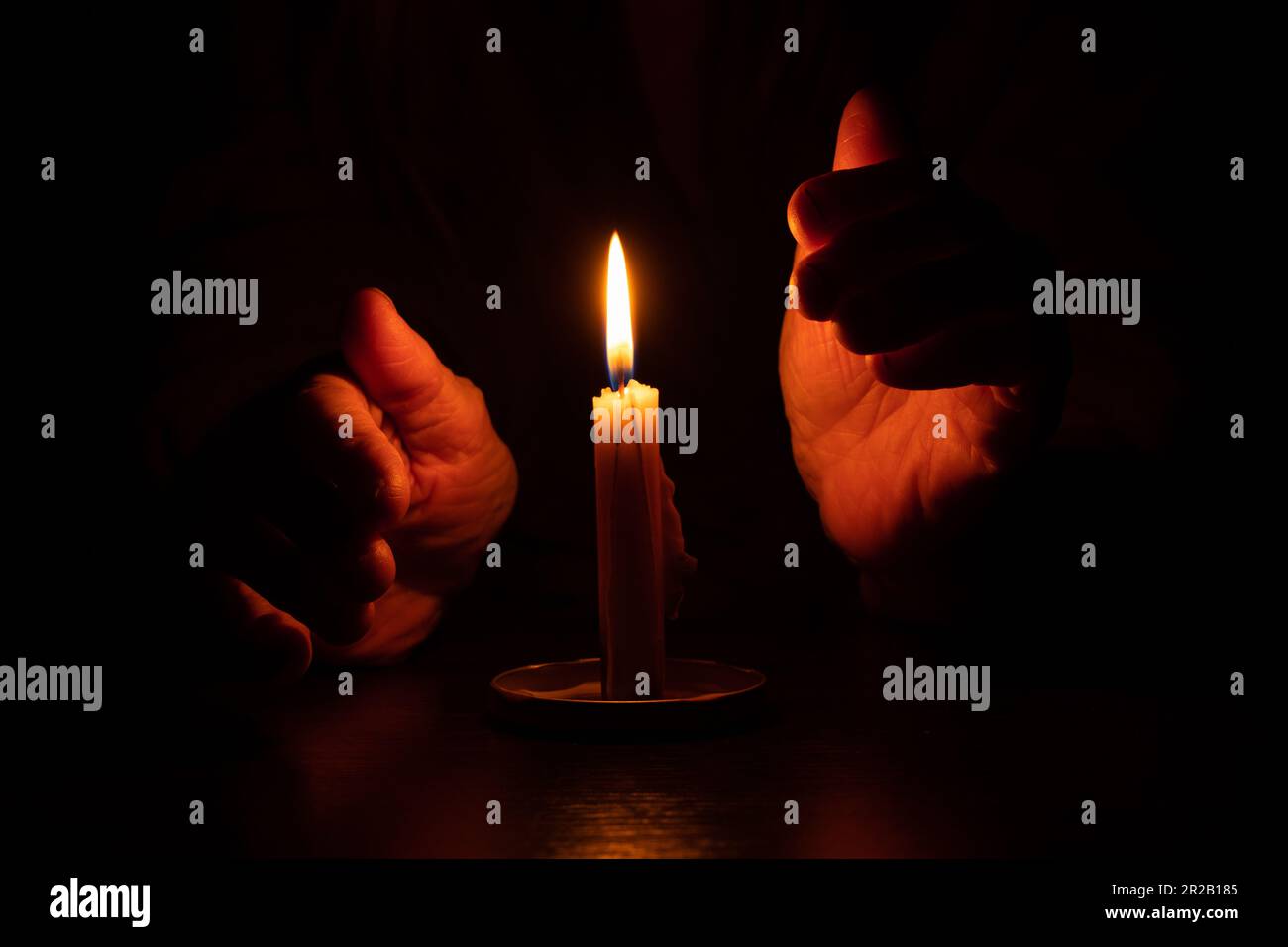 old woman's hands and candle flame in the dark, candle light, mourning ...