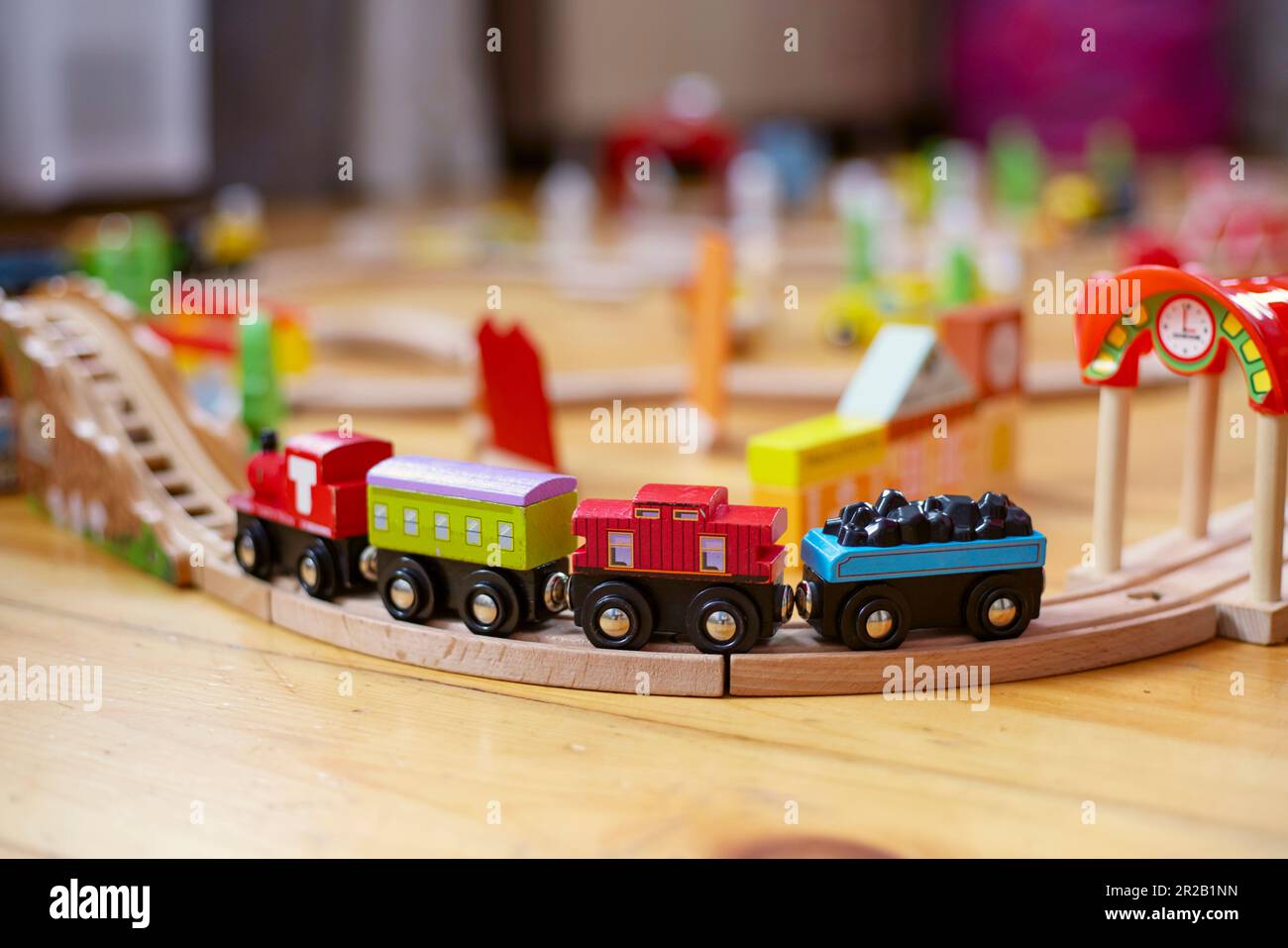 Wooden toy train on railroad with brick town on floor. Toys for kids ...