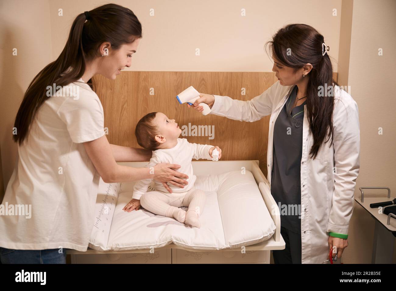 Focused pediatric doctor taking baby temperature in hospital ward Stock ...