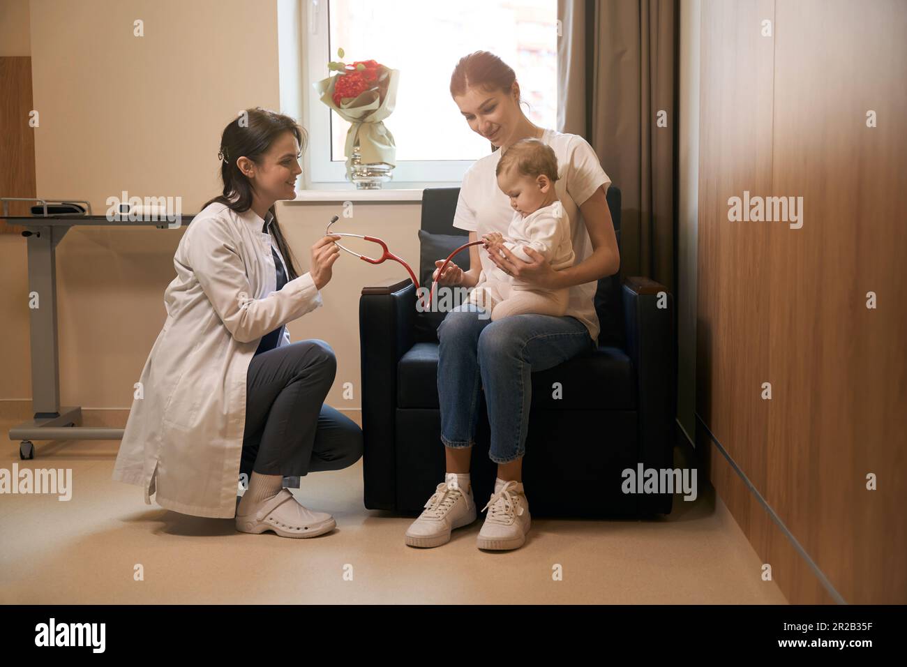Pediatrician demonstrating medical instrument to child during morning ...