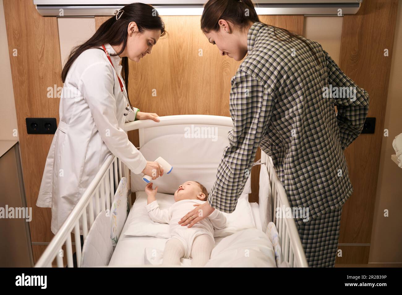 Serious pediatrician measuring child temperature in hospital ward Stock ...