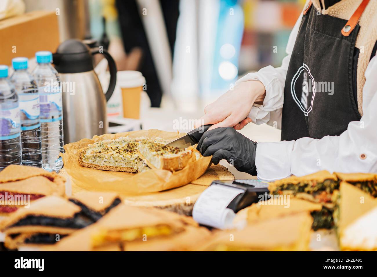 Girl Chef cook in apron and gloves cuts freshly baked pie in market ...