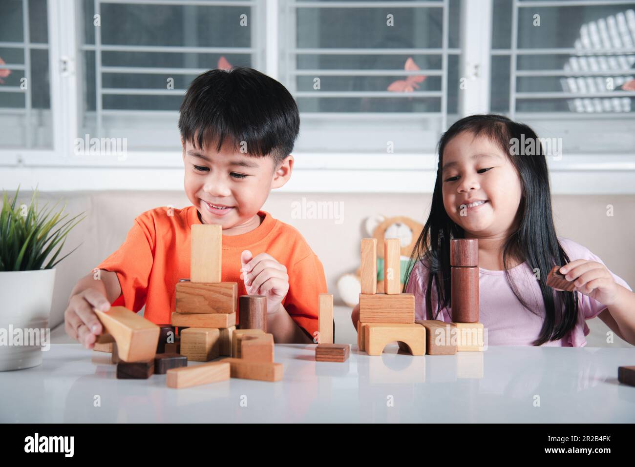Children boy and girl playing with constructor wooden block building ...