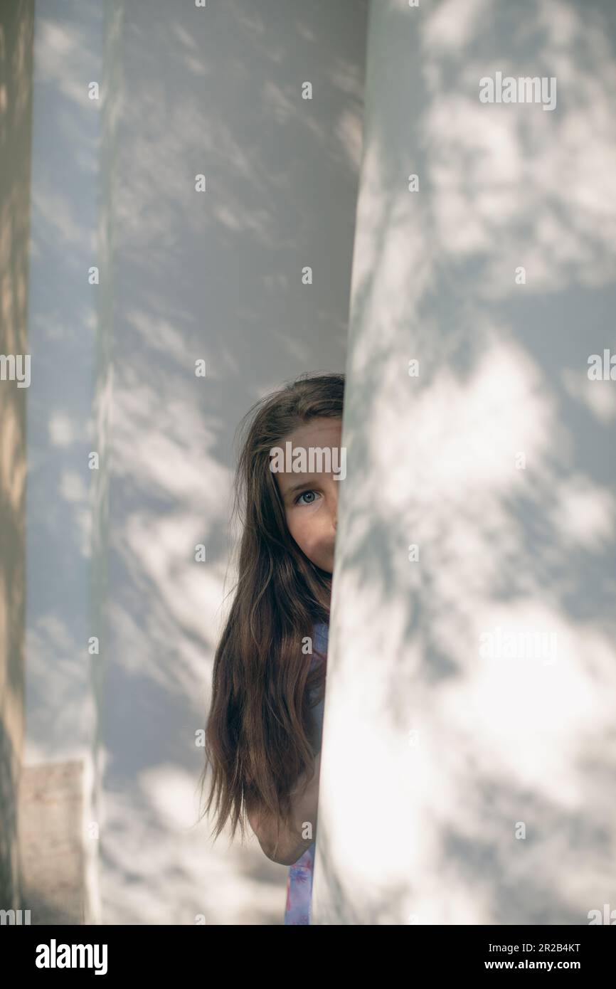 Beautiful girl peeking out from behind the column Stock Photo - Alamy