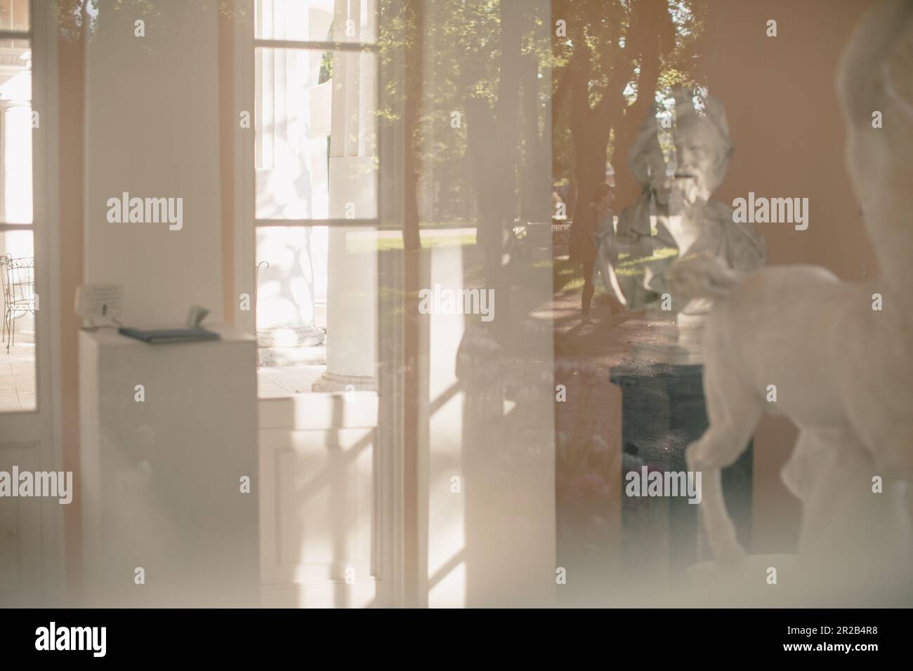 Statue behind the window of glass with reflection of beautiful garden ...