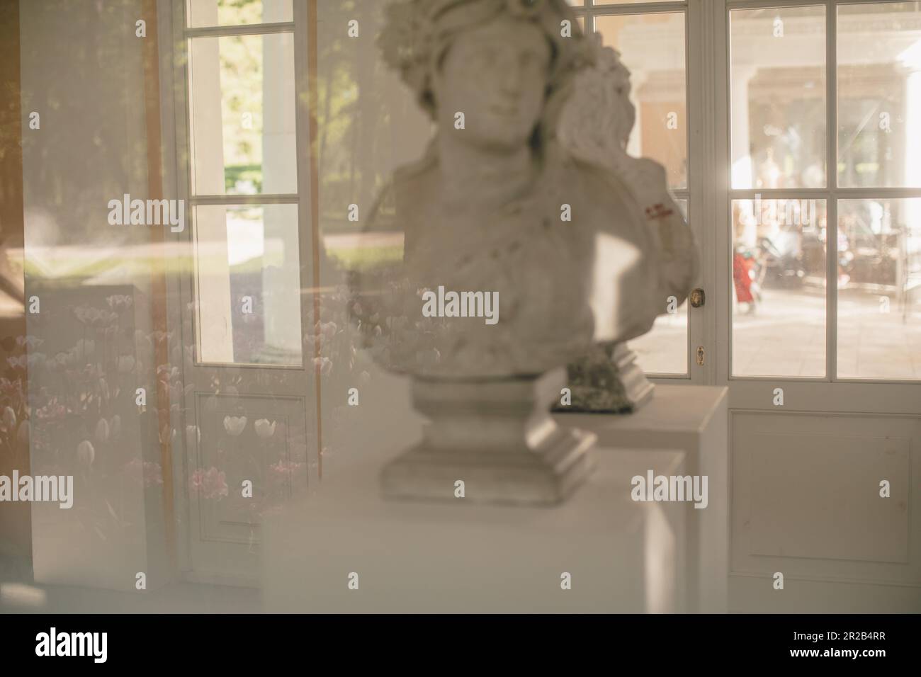 Statue behind the window of glass with reflection of beautiful garden ...