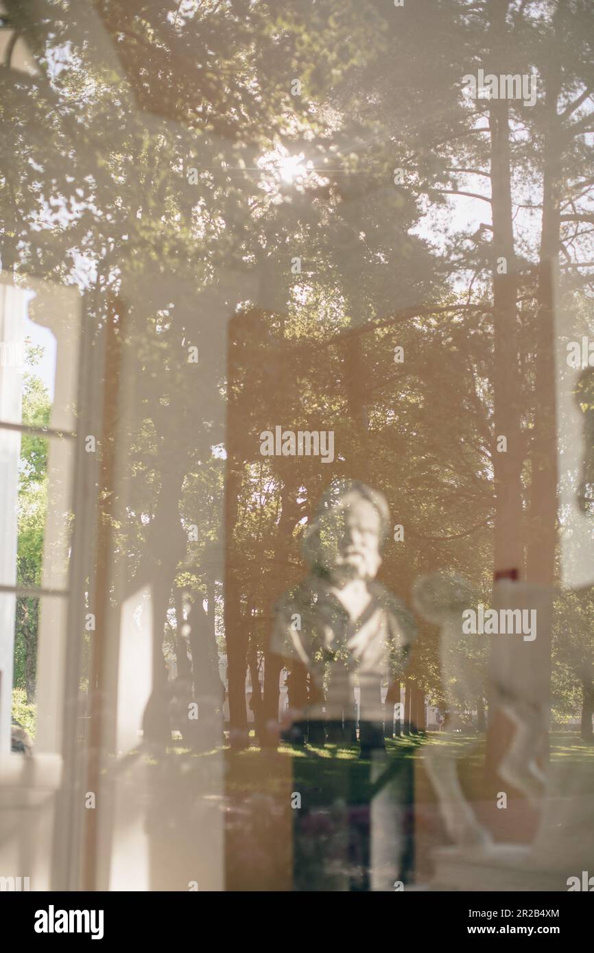 Statue behind the window of glass with reflection of beautiful garden ...