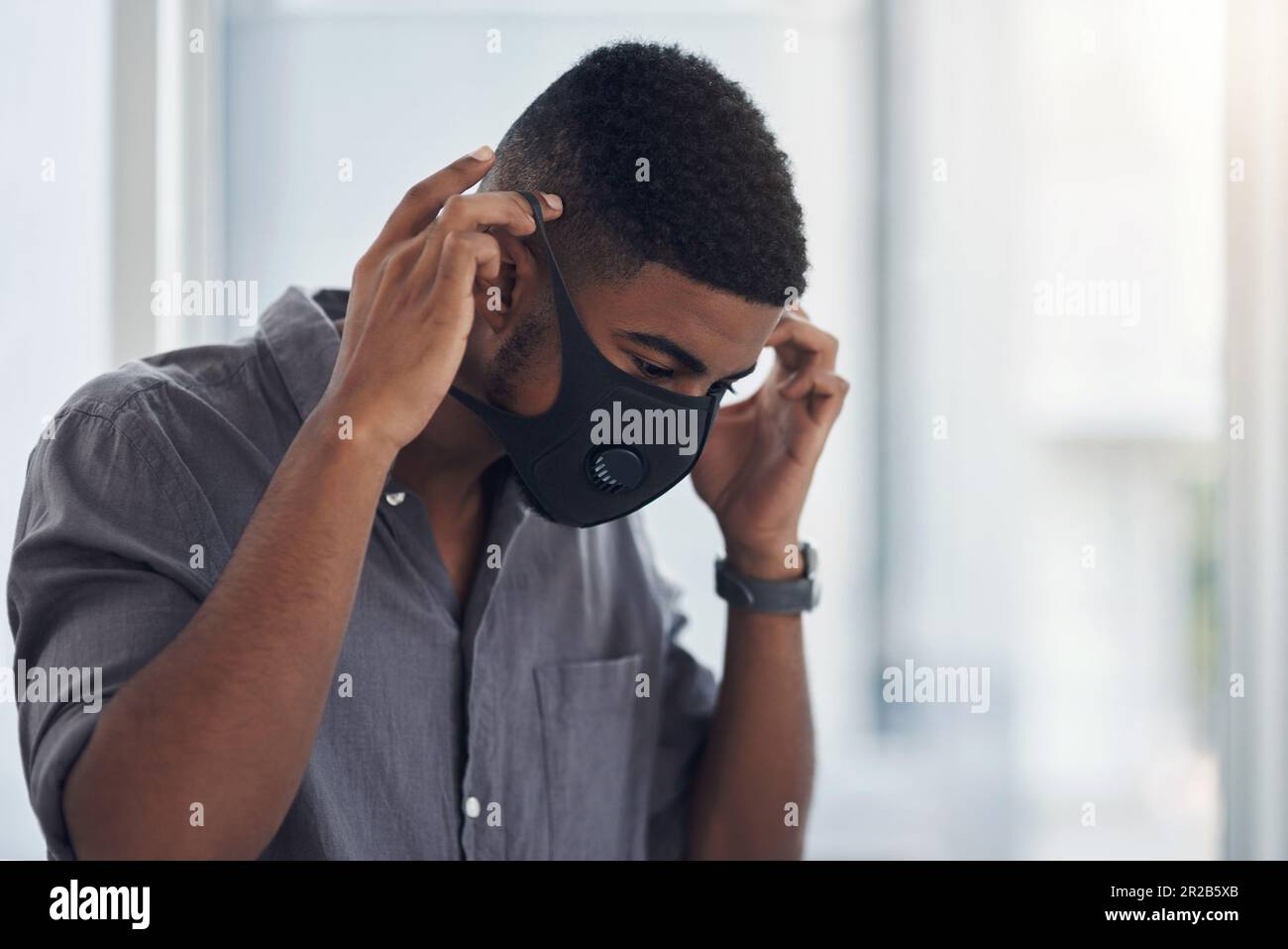 Wearing a face mask has become compulsory at his workplace. a young ...