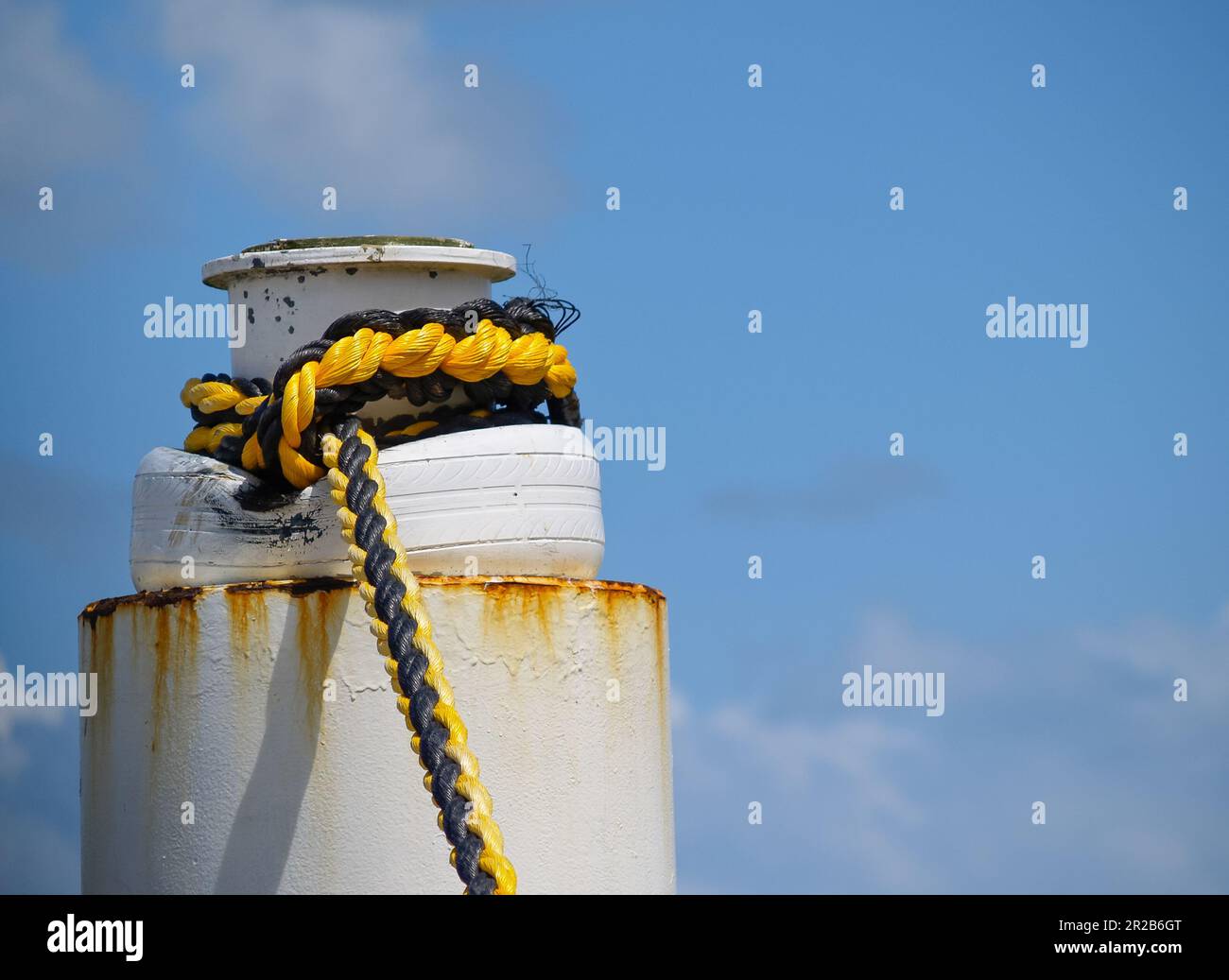Large white mooring pile with bright yellow and black rope for tying up ...