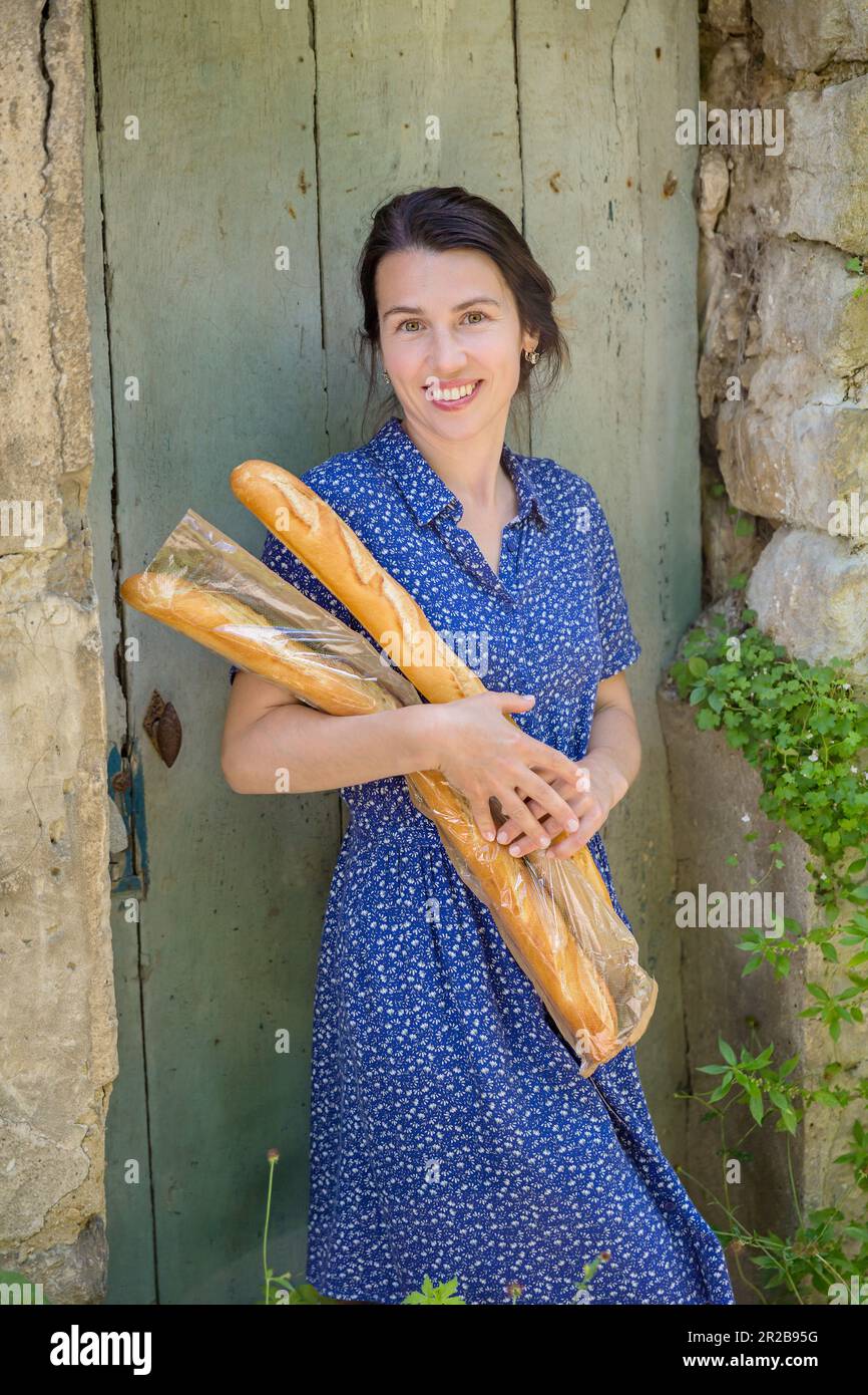Young woman standing with french baguettes in the countryside Stock ...
