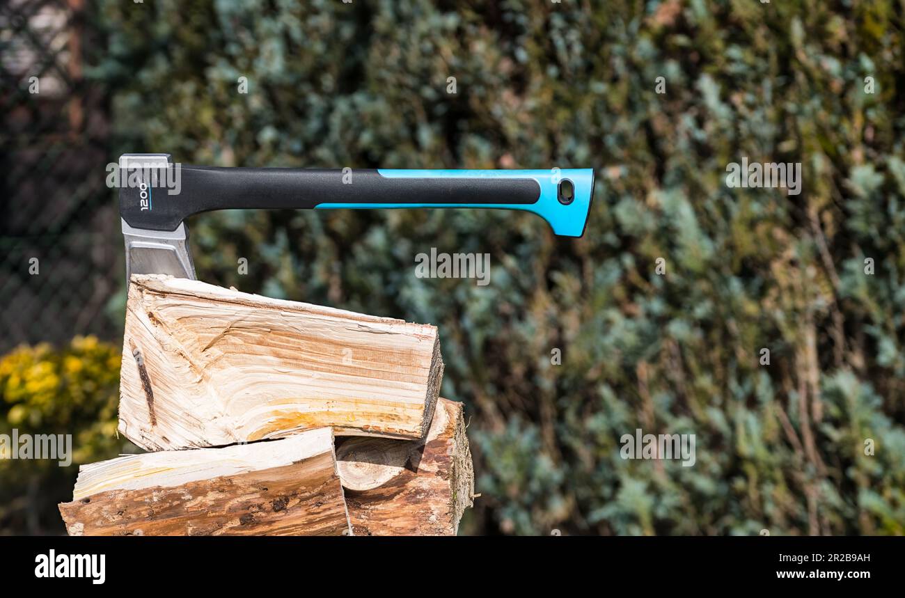 Modern splitting axe on pile of chopped woods on blurry green ...