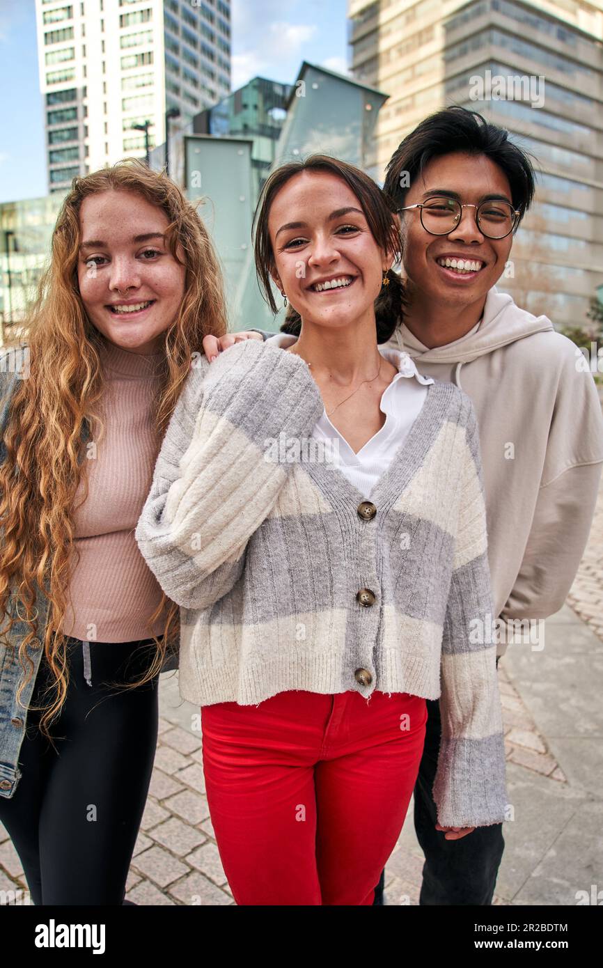 Vertical portrait three smiling multiracial young college students ...