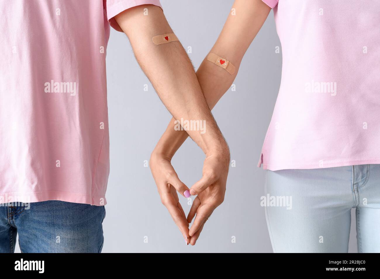 Young couple after donating blood holding hands on light background ...