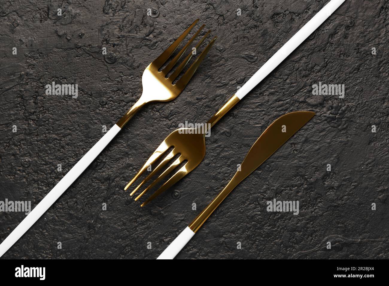 Golden forks and knife with white handles on black background Stock ...