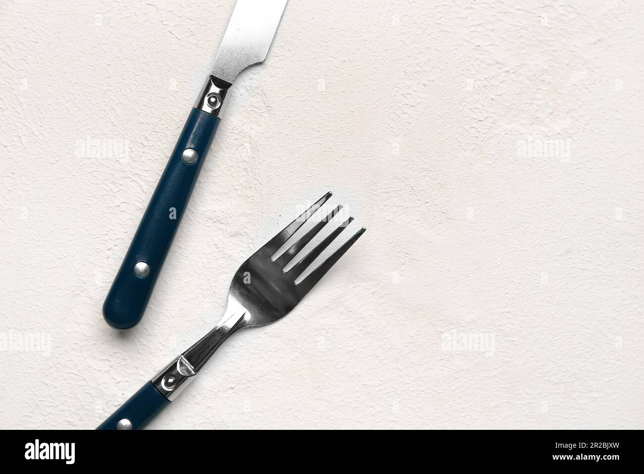 Stainless steel fork and knife with blue handles on white background ...