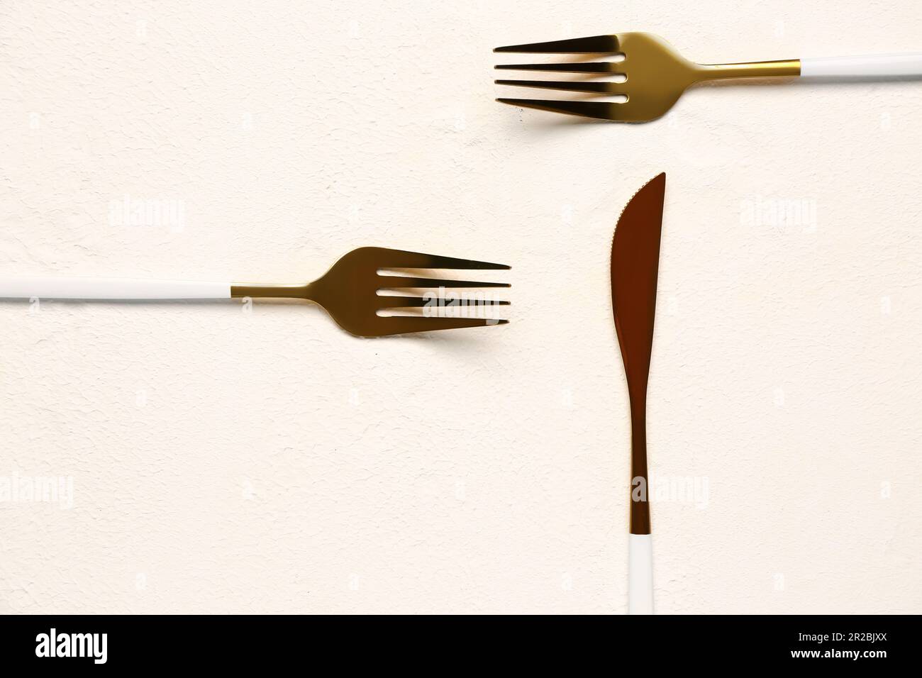Golden forks and knife with colored handles on white background Stock ...