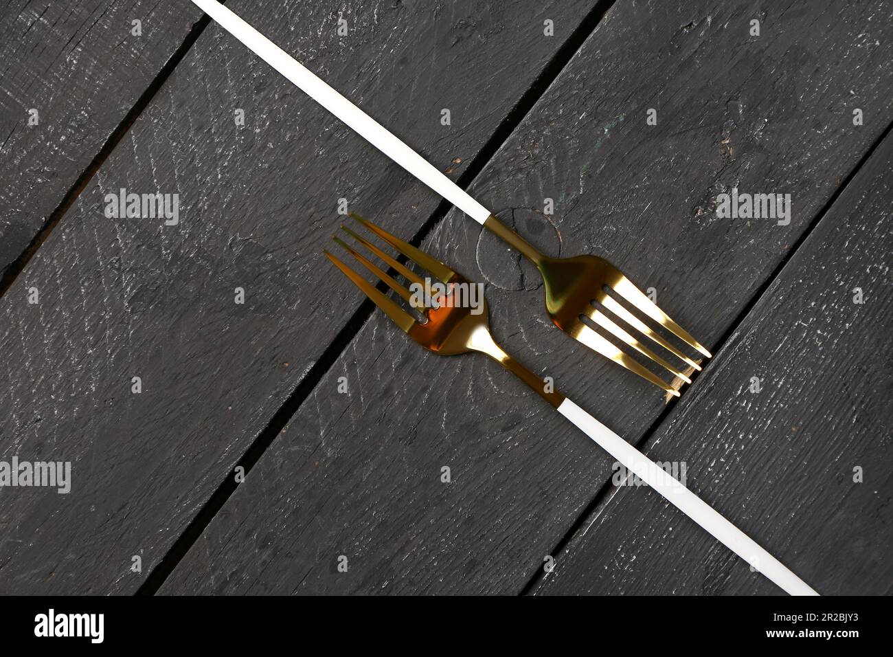 Golden forks with white handles on black wooden background Stock Photo ...