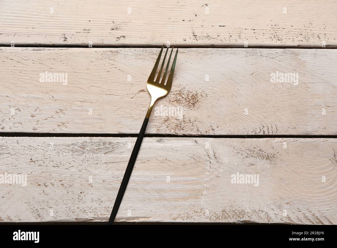 Golden fork with black handle on white wooden background Stock Photo ...