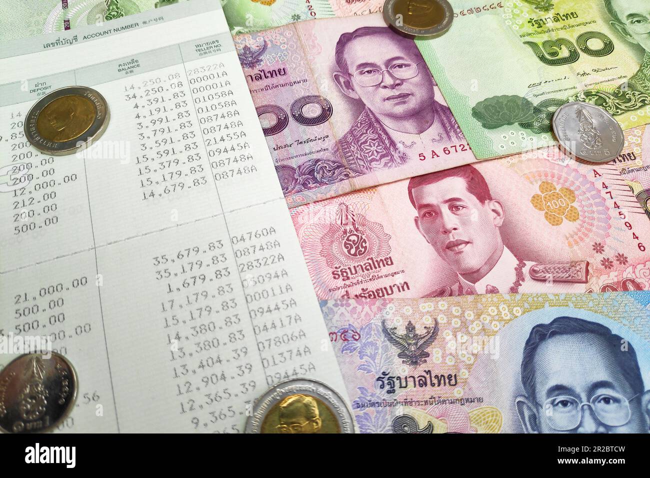 Close-up on a passbook with some Thai coins and banknotes Baths. The ...