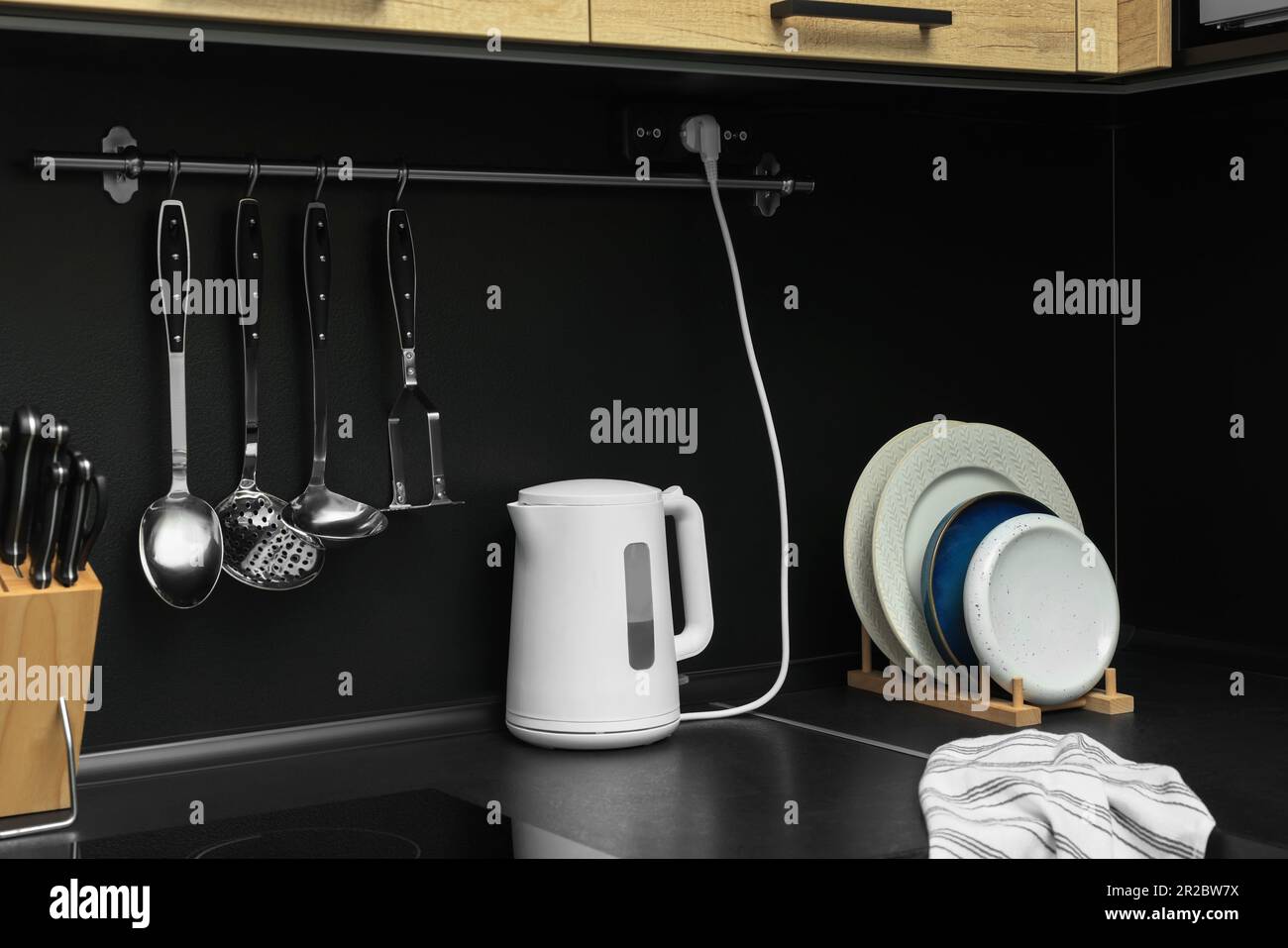 Electric kettle and kitchen utensils on black countertop Stock Photo ...