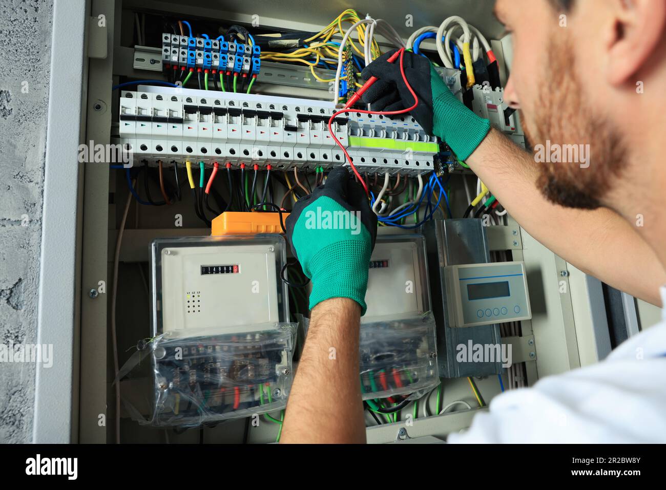 Electrician checking electric current with multimeter indoors, closeup ...