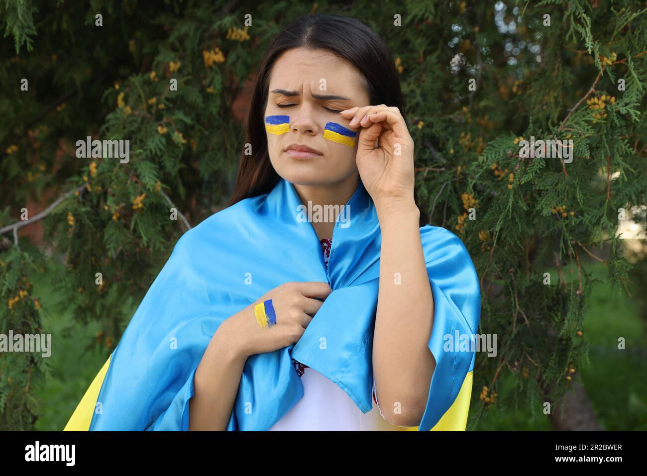 Sad young woman with Ukrainian flag outdoors Stock Photo - Alamy