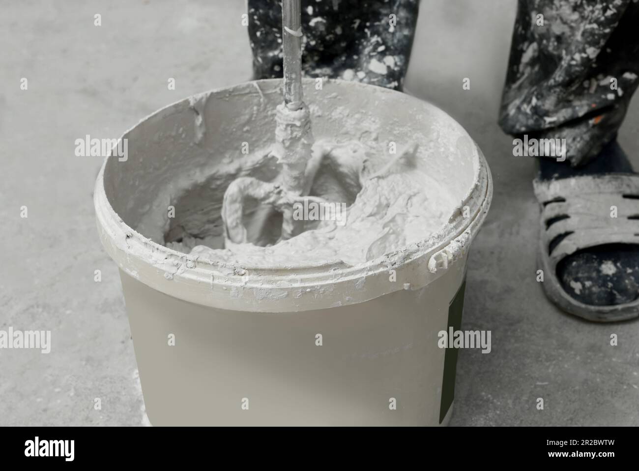 Professional worker mixing plaster in bucket indoors, closeup Stock ...