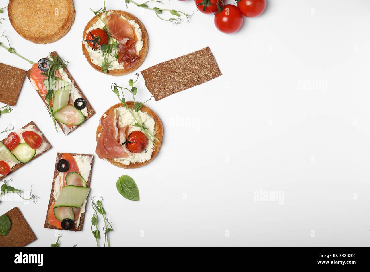 Tasty rusks and rye crispbreads with different toppings on white ...