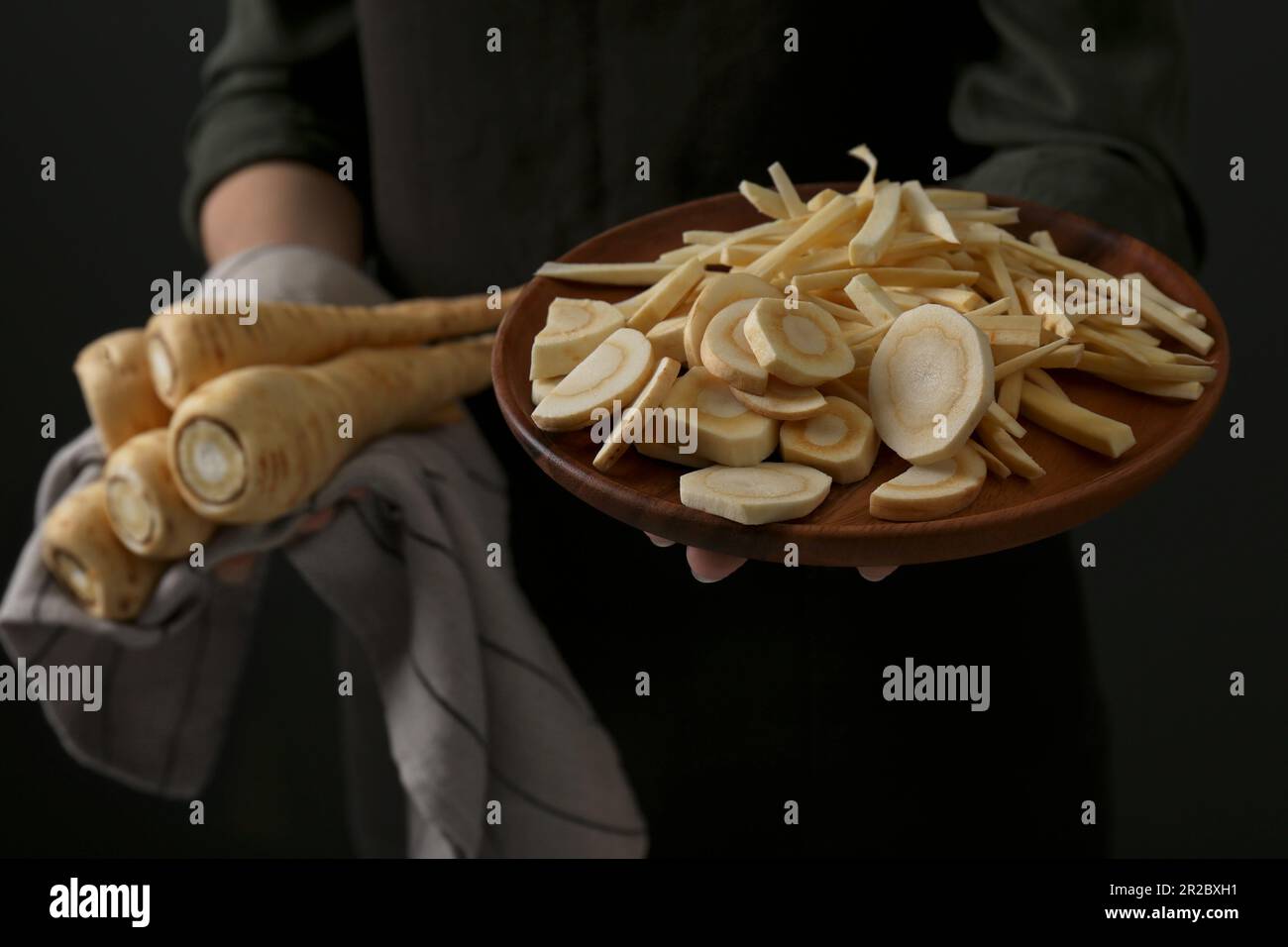 Woman holding whole and cut parsnips on black background, closeup Stock ...