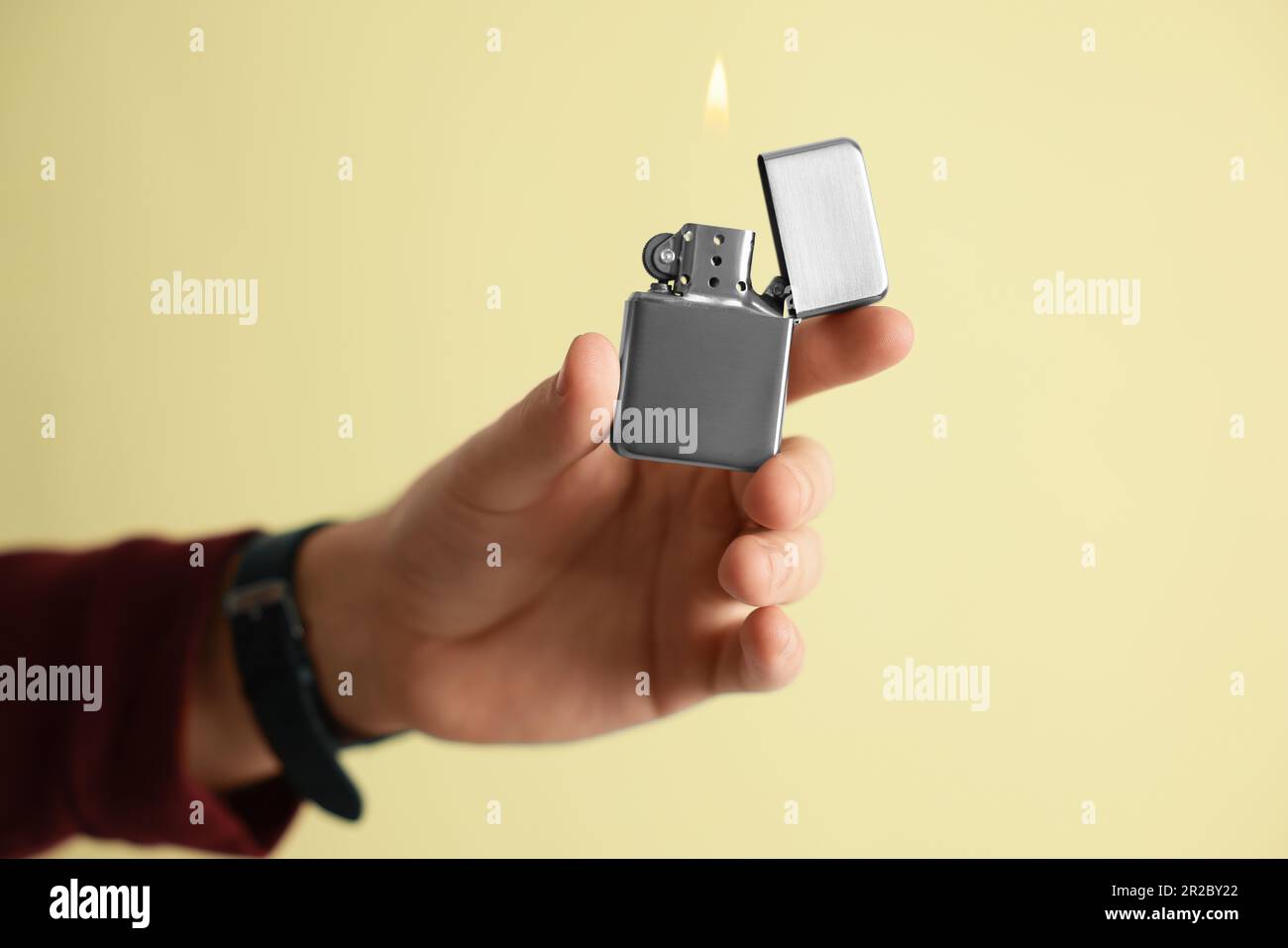 Man holding lighter with burning flame against beige background ...
