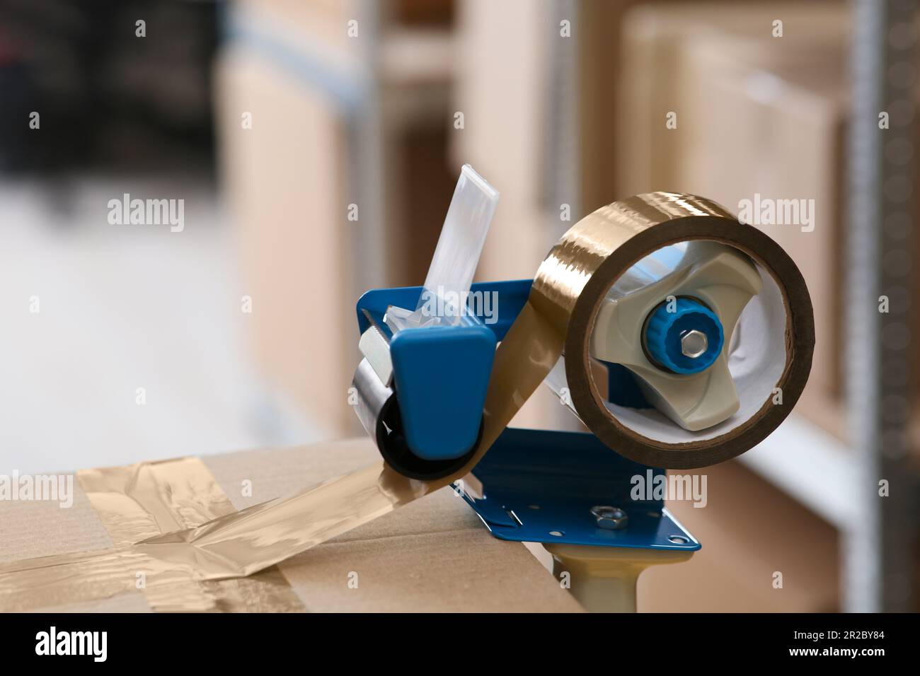 Taping cardboard box with adhesive tape dispenser indoors, closeup ...