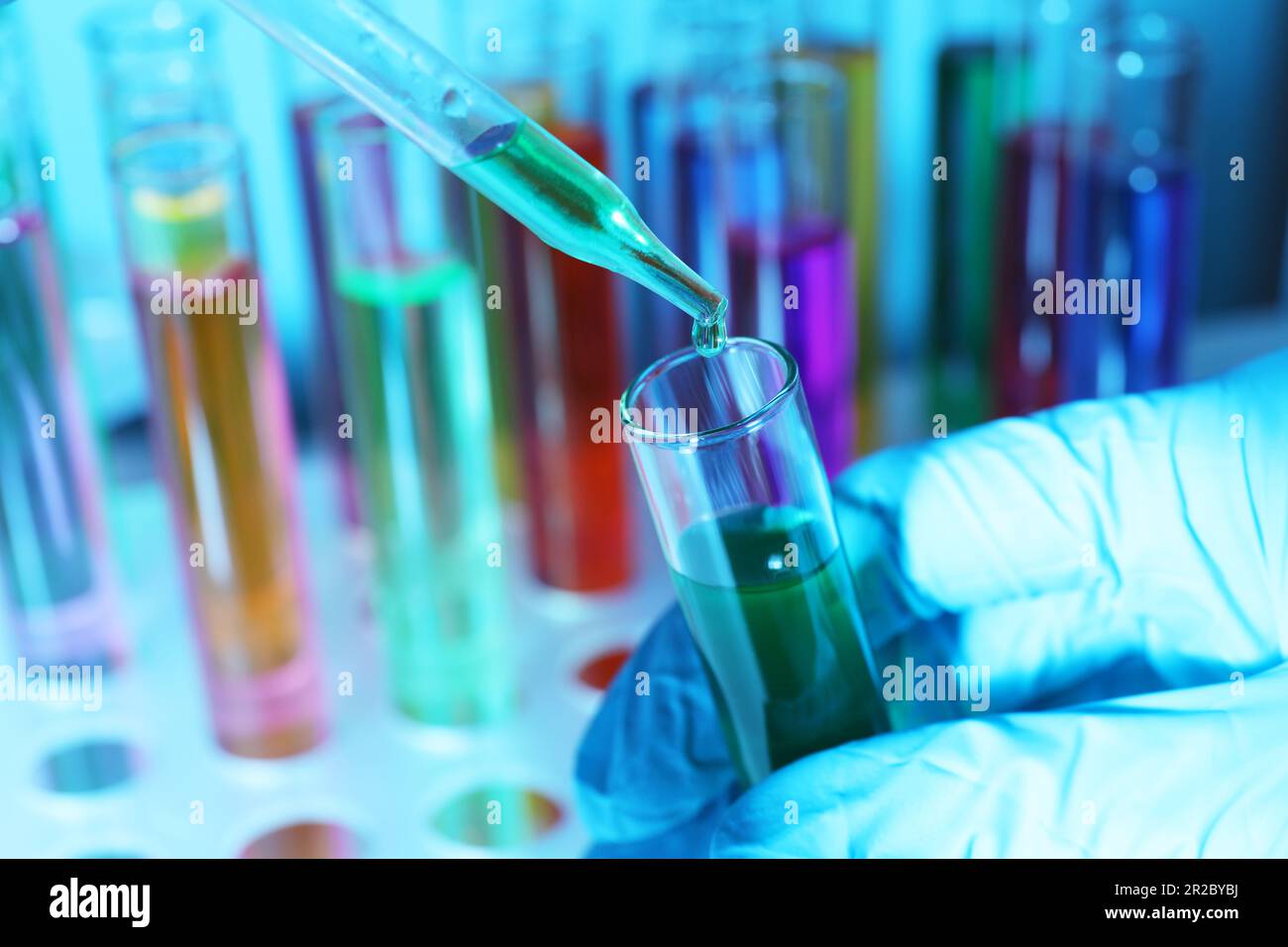Scientist dripping liquid from pipette into test tube against ...