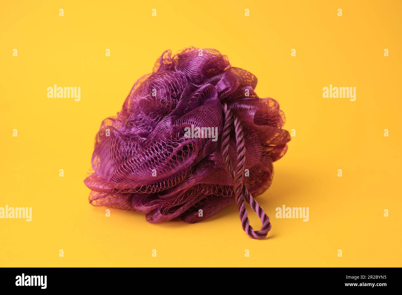 Purple shower puff on yellow background. Personal hygiene Stock Photo ...