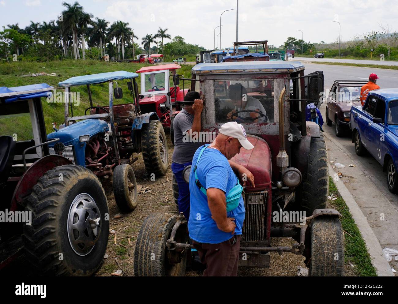 Farm workers wait with their tractors in a line to be able to refuel ...