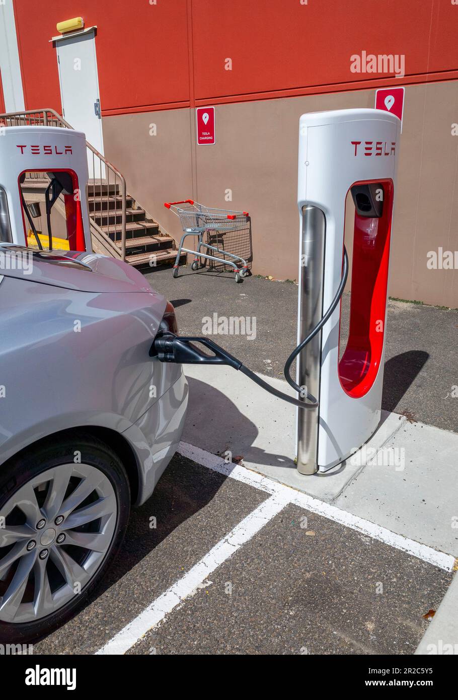 Silver Tesla 3 charging at electric vehicle charging station in ...