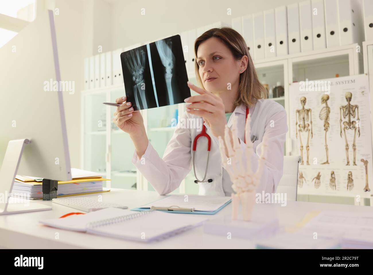 Doctor studies X-ray picture of patient arm sitting at desk Stock Photo ...