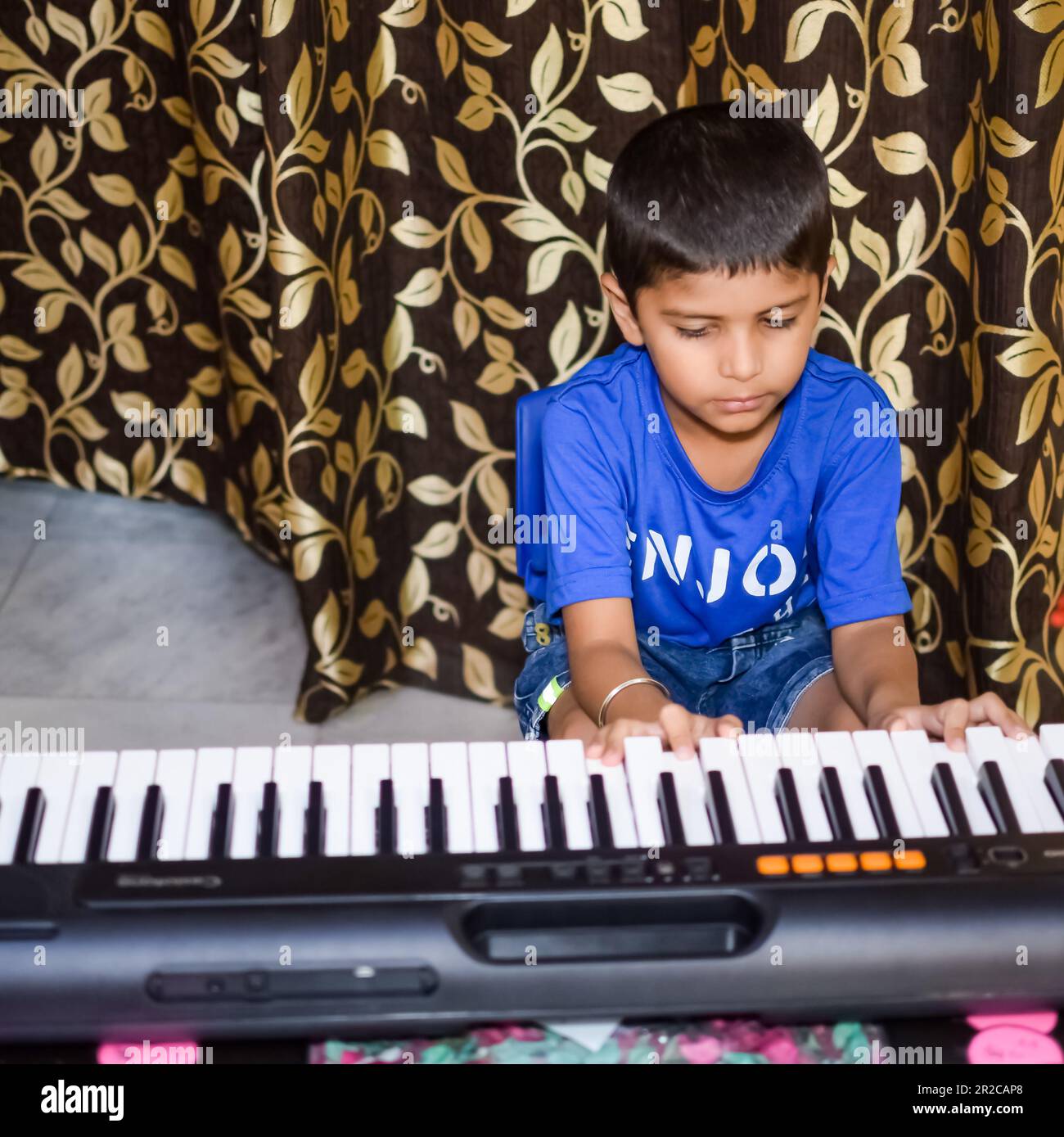 Asian boy playing the synthesizer or piano. Cute little kid learning ...