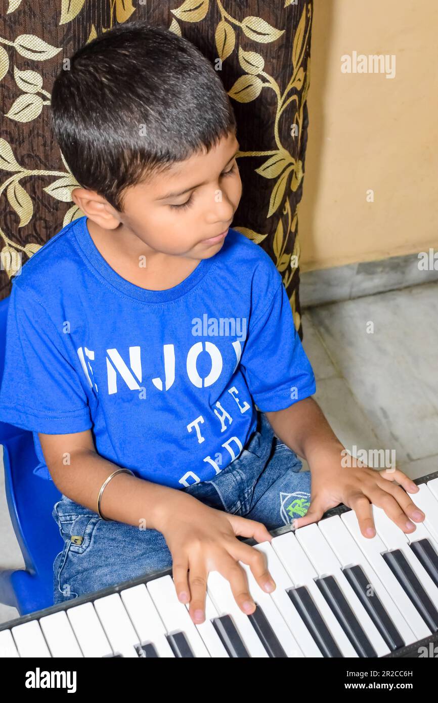 Asian boy playing the synthesizer or piano. Cute little kid learning ...
