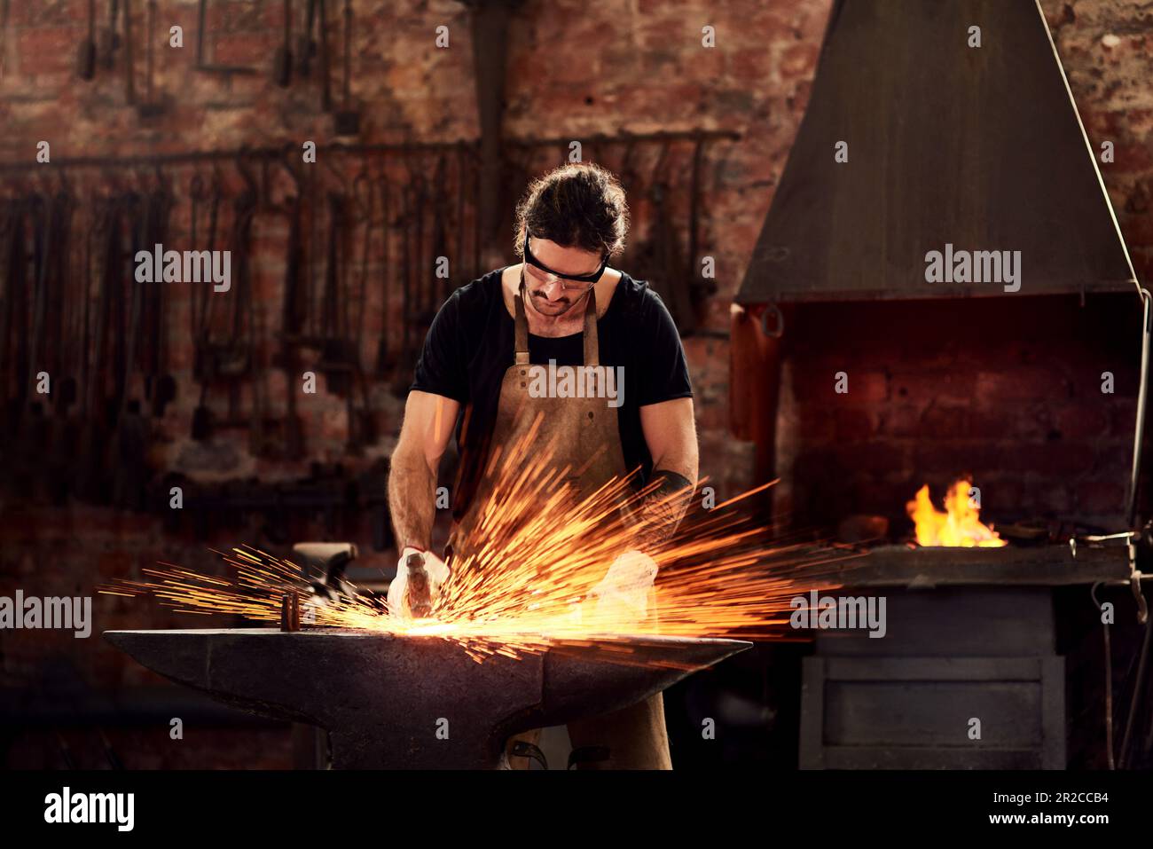 Blacksmith, man and metal workshop and sparks, manual forge working on ...