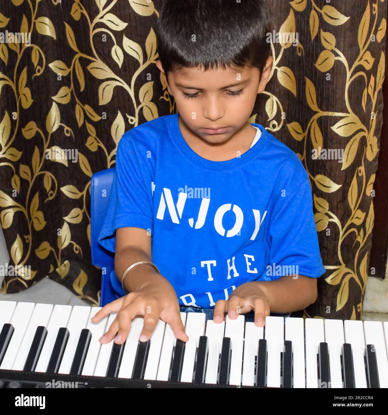 Asian boy playing the synthesizer or piano. Cute little kid learning ...