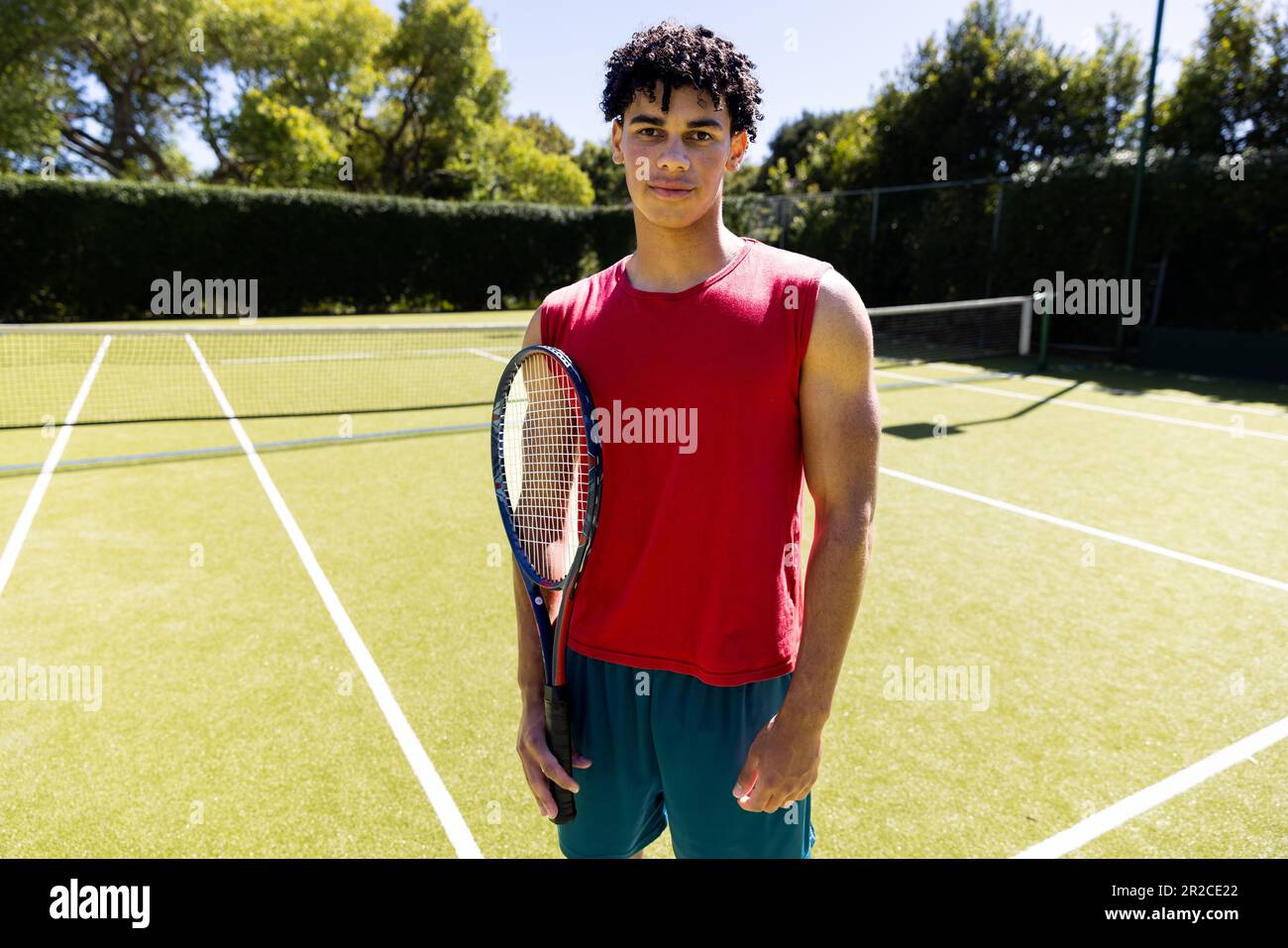 Portrait of happy fit biracial man holding tennis racket on sunny ...
