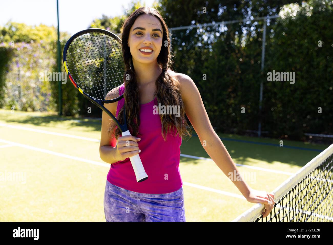 Portrait of happy fit caucasian woman holding tennis racket, at net on ...