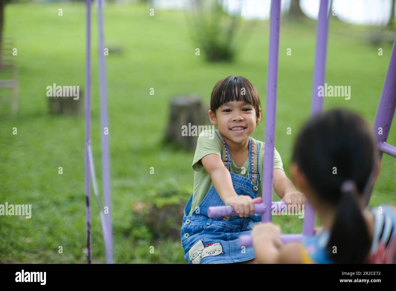 Two cute little sisters having fun playing in the playground during ...
