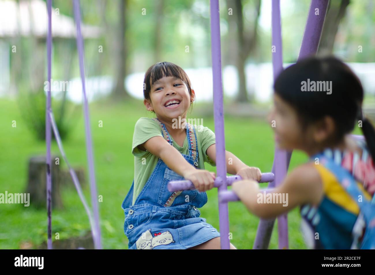 Two cute little sisters having fun playing in the playground during ...
