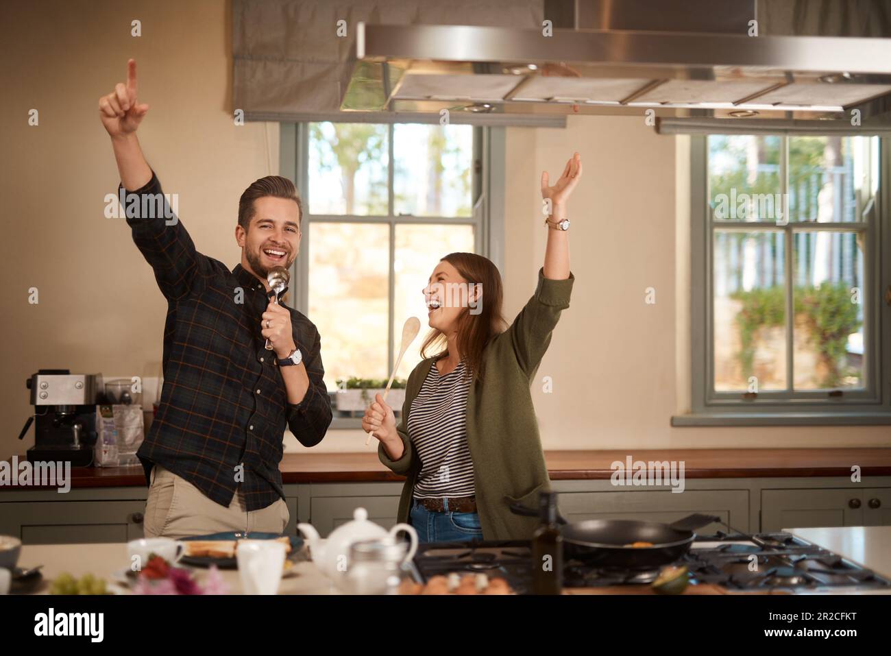 Food, sing and a funny couple in the kitchen of their home, having fun ...