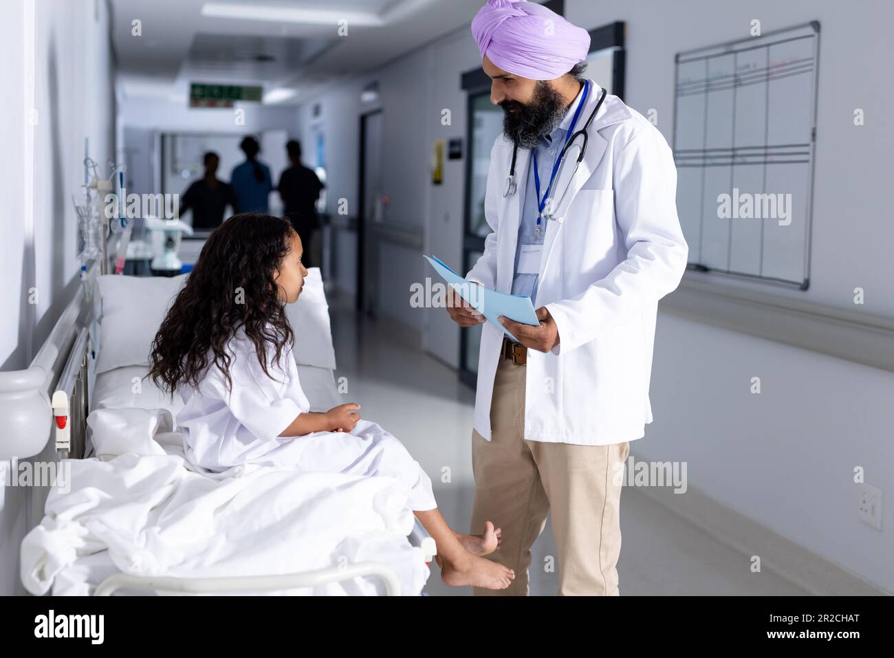 Happy sikh male doctor in turban and biracial girl patient talking in ...