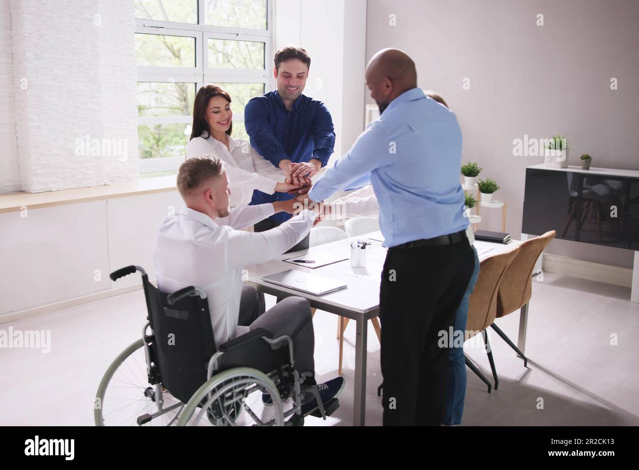 Businesspeople Stacking Their Hands Over Wooden Desk Stock Photo - Alamy