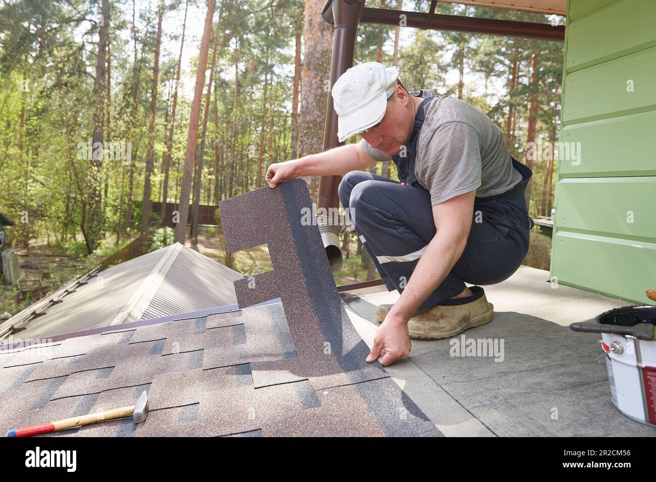 A man lays a roof of soft tiles on the roof of a country house Stock ...